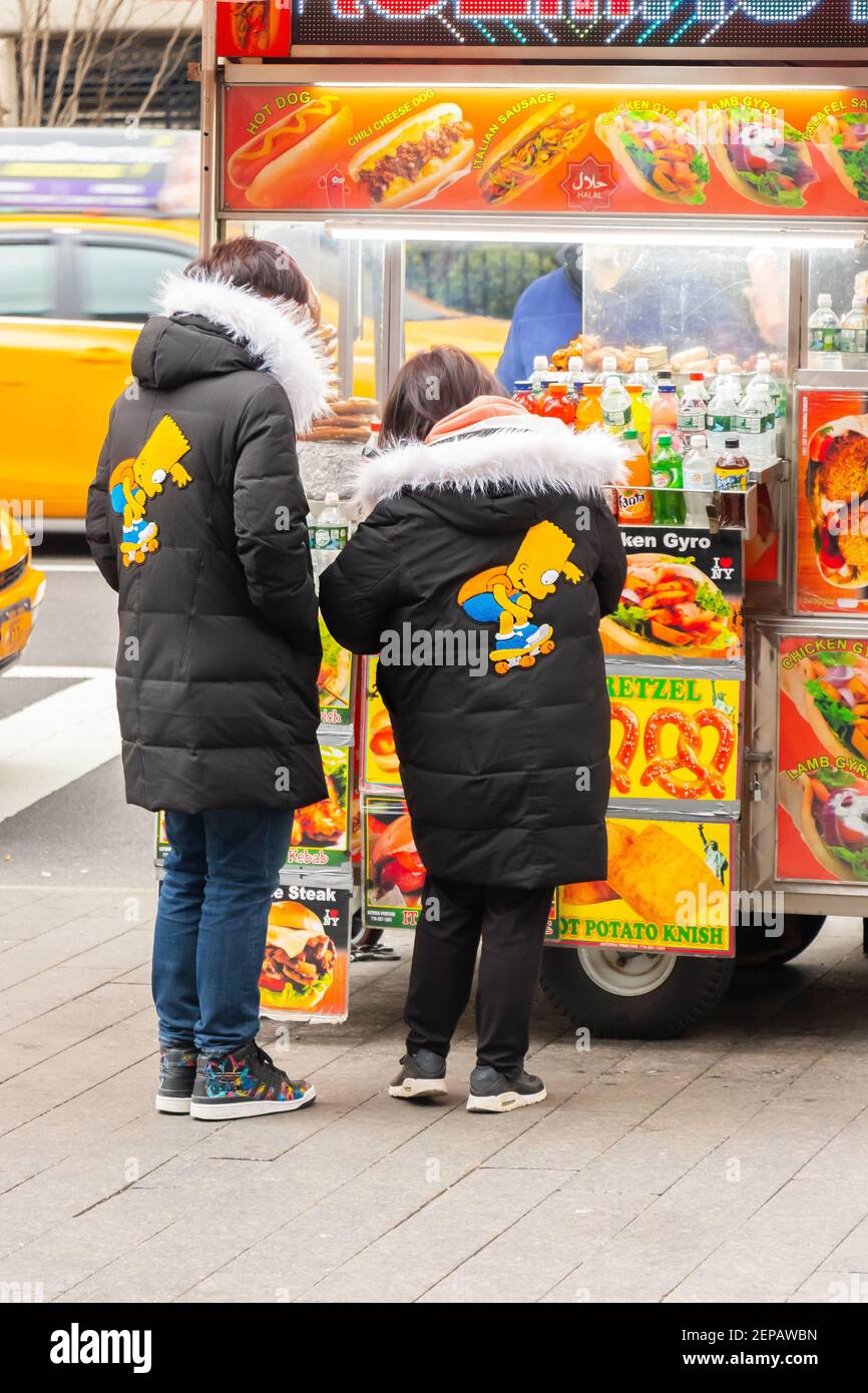 asian couple in identical Simpsons coats at food stands outside of New ...