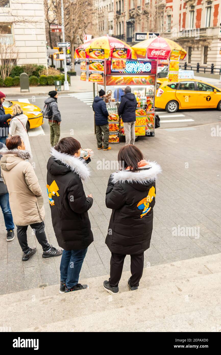 asian couple in identical Simpsons coats at food stands outside of New ...