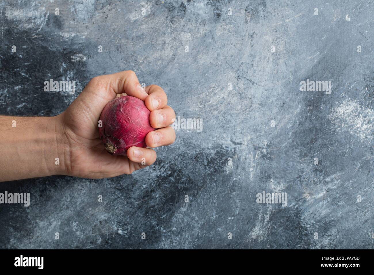 Male hand holding single red onion on marble background Stock Photo - Alamy