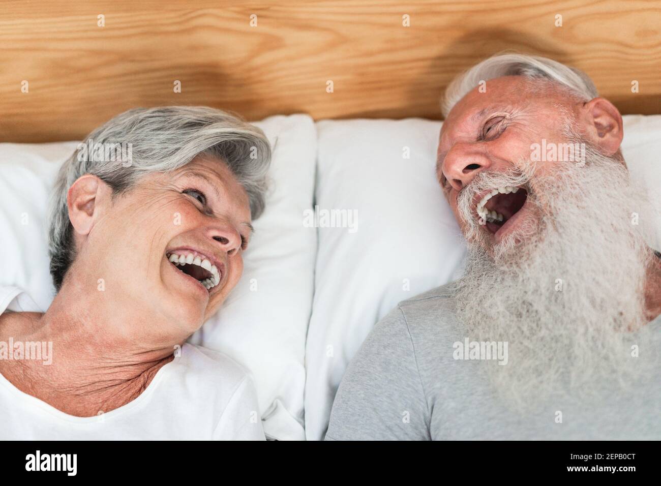 Happy married senior couple having fun lying in bed - Main focus on ...