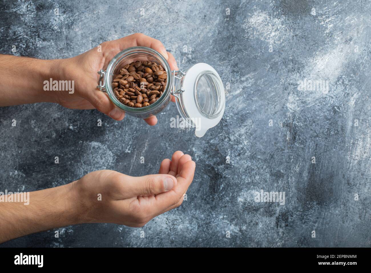 Male hand holding glass jar of aromatic coffee beans on marble ...