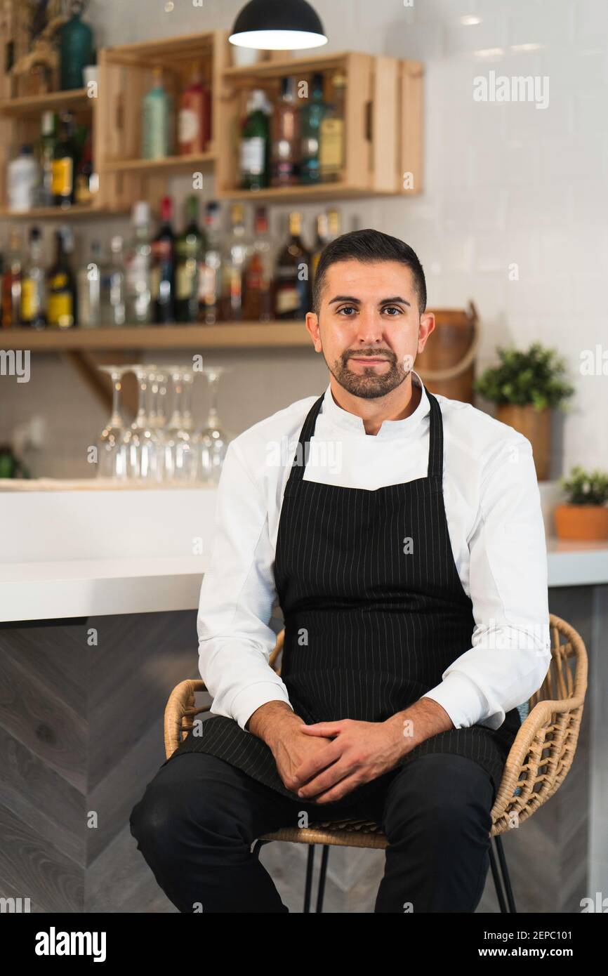 Portrait of a Happy young chef posing wearing uniform and kitchen gown ...