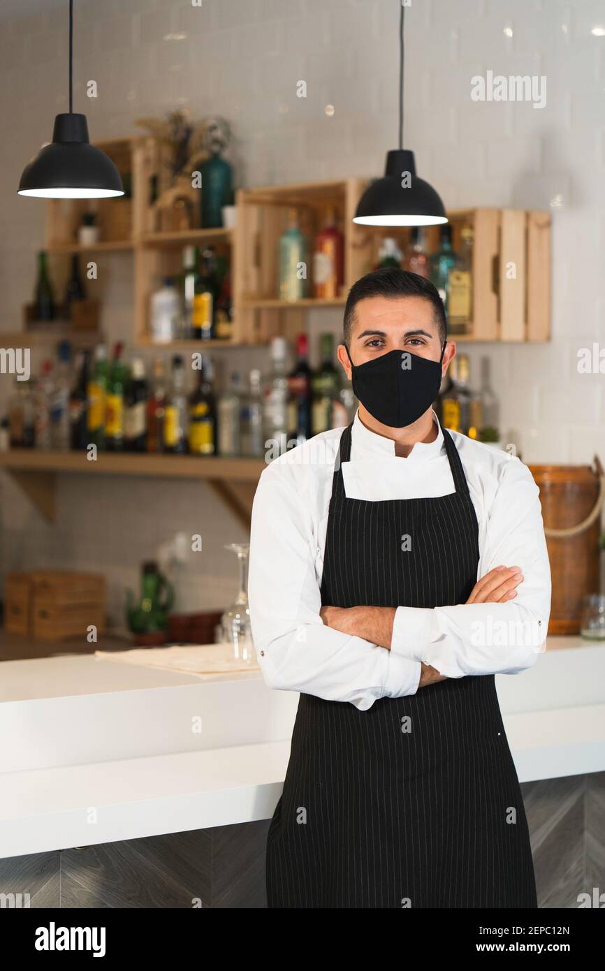 Portrait of a Young chef posing wearing mask uniform and kitchen gown ...