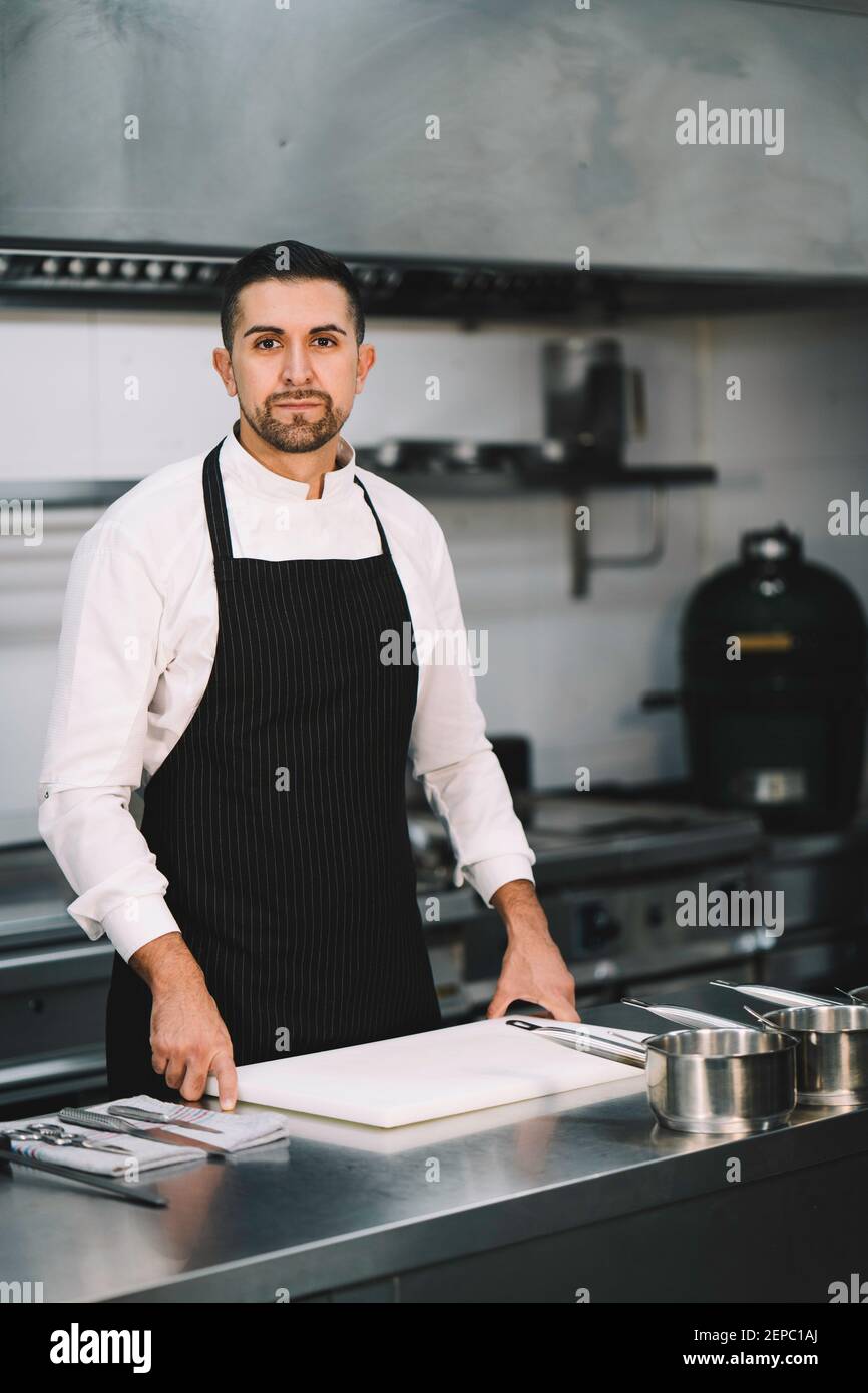 Portrait of a Professional chef posing and wearing uniform and gown in ...