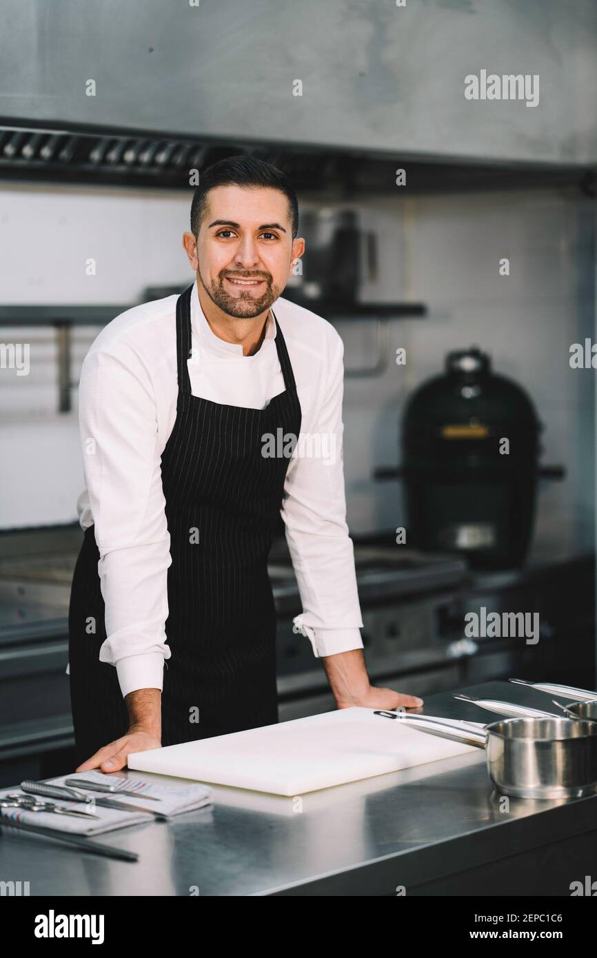 Portrait of a Professional chef posing and wearing uniform and gown in ...