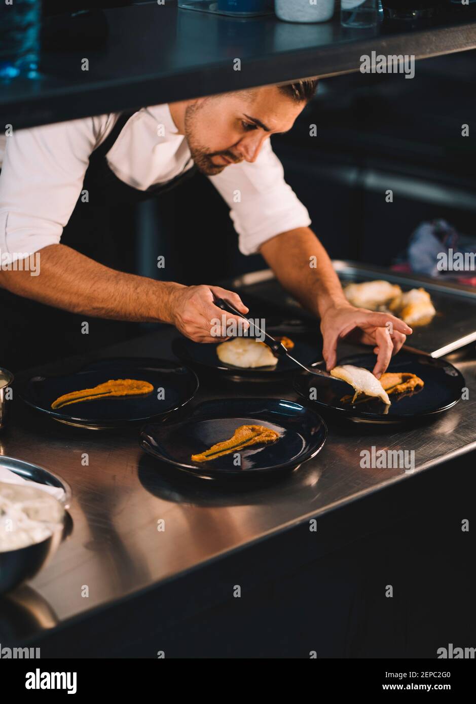 Portrait of a male chef decorating food in ceramic dishes over ...