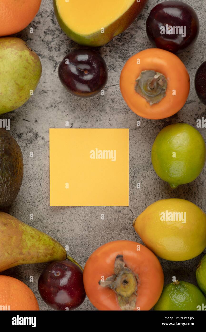 Bunch of delicious fresh fruits and empty memo pad on marble surface ...