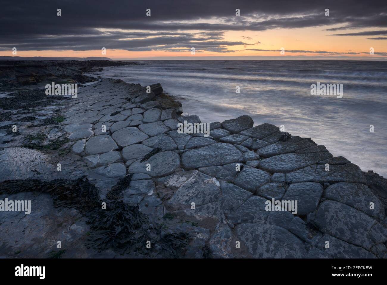 Limestone pavements surrounded by the incoming tide at Kilve Beach ...