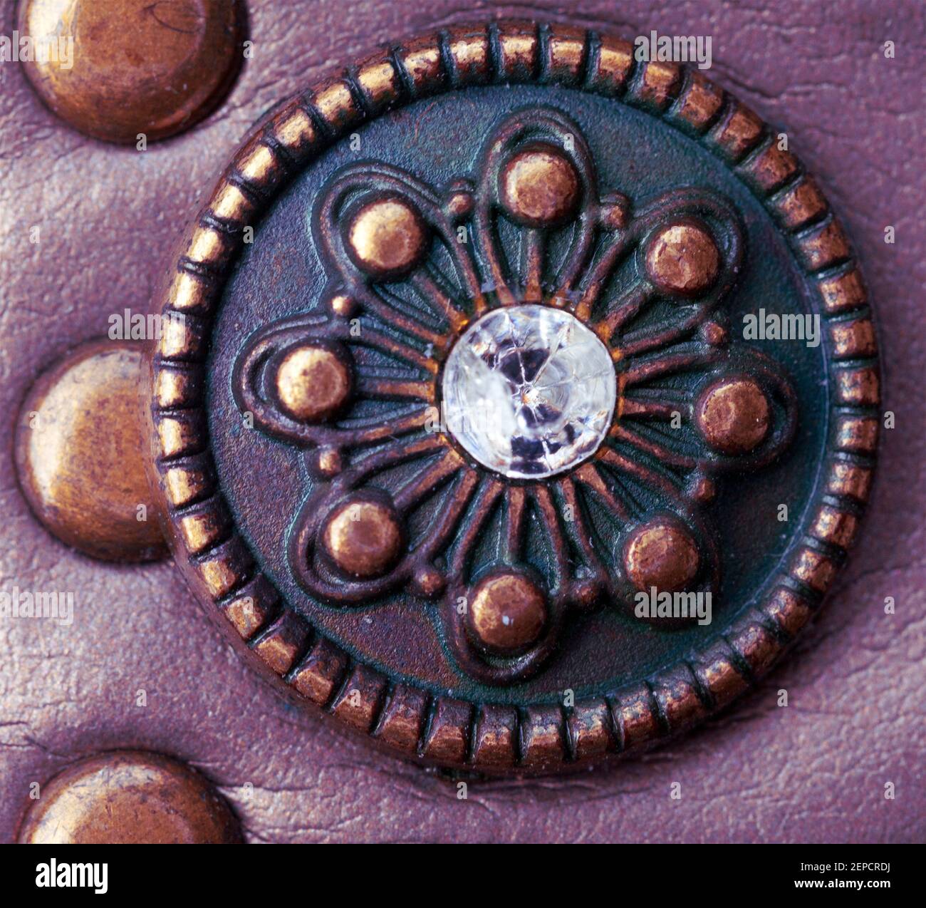 Macro shot of a copper medaillon with flower pattern and a light ...