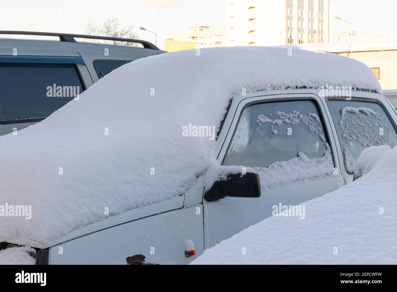 old white abandoned broken rusty car parked by the road under a large ...