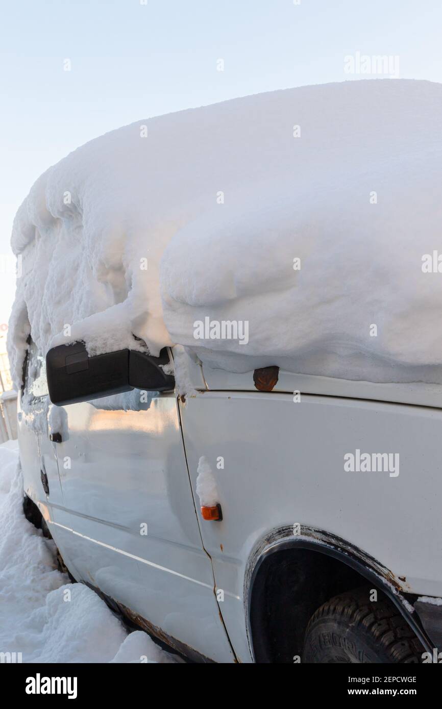 old white abandoned broken rusty car parked by the road under a large ...