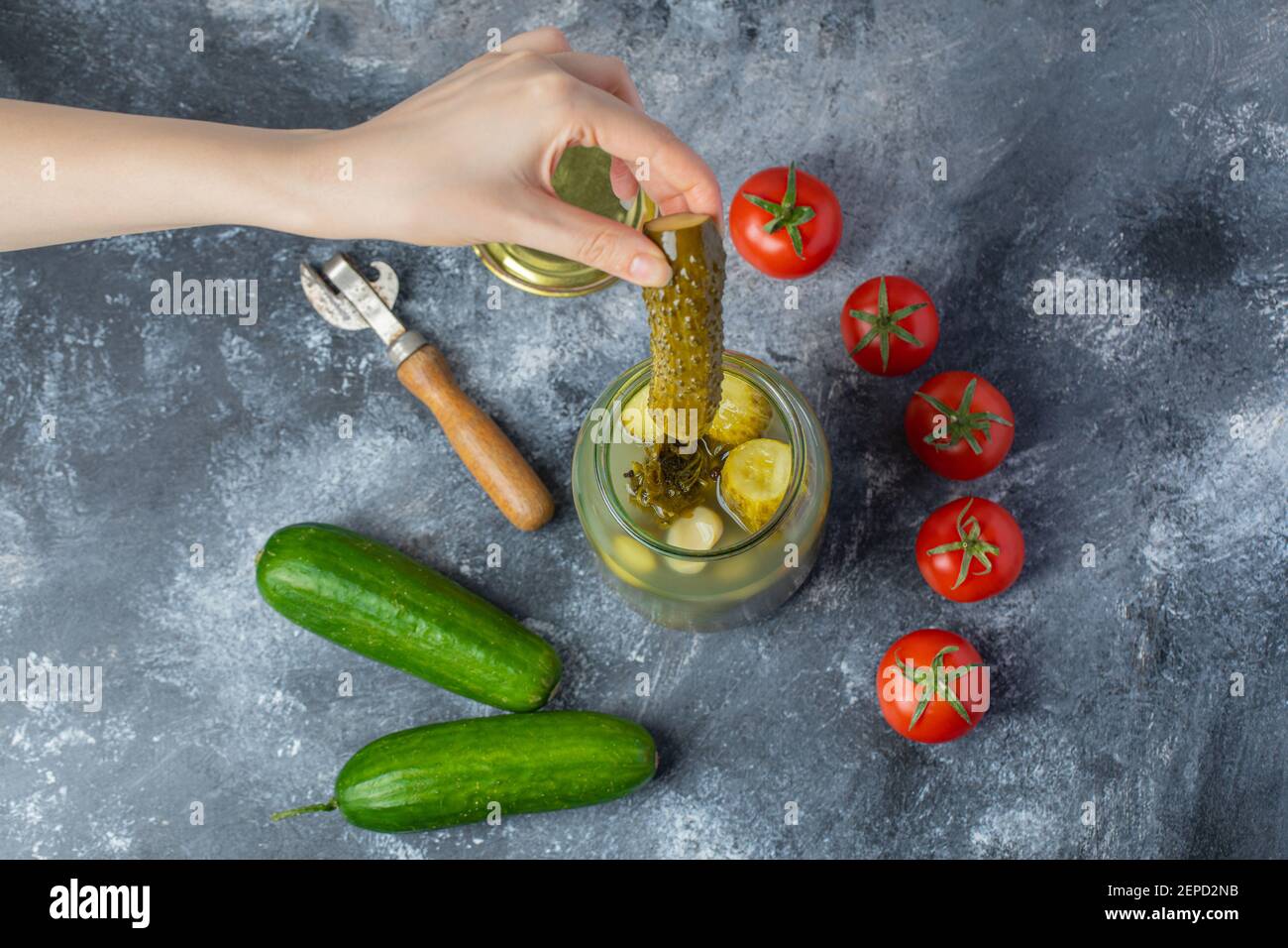 Fresh vegetables with jar of pickle. Female hand taking pickle from jar ...