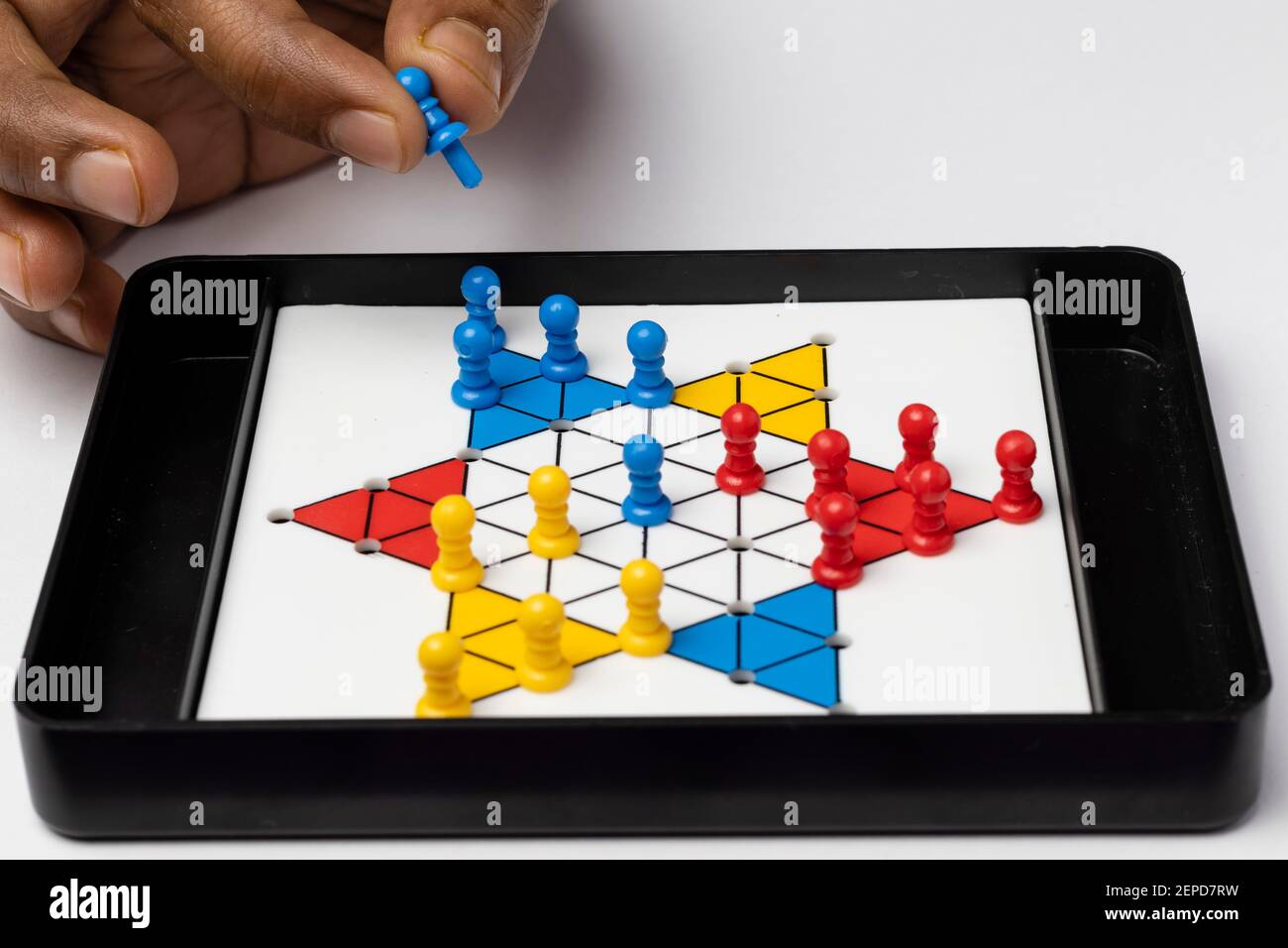 Close-up of a board game - chinese checkers with human hand on white ...