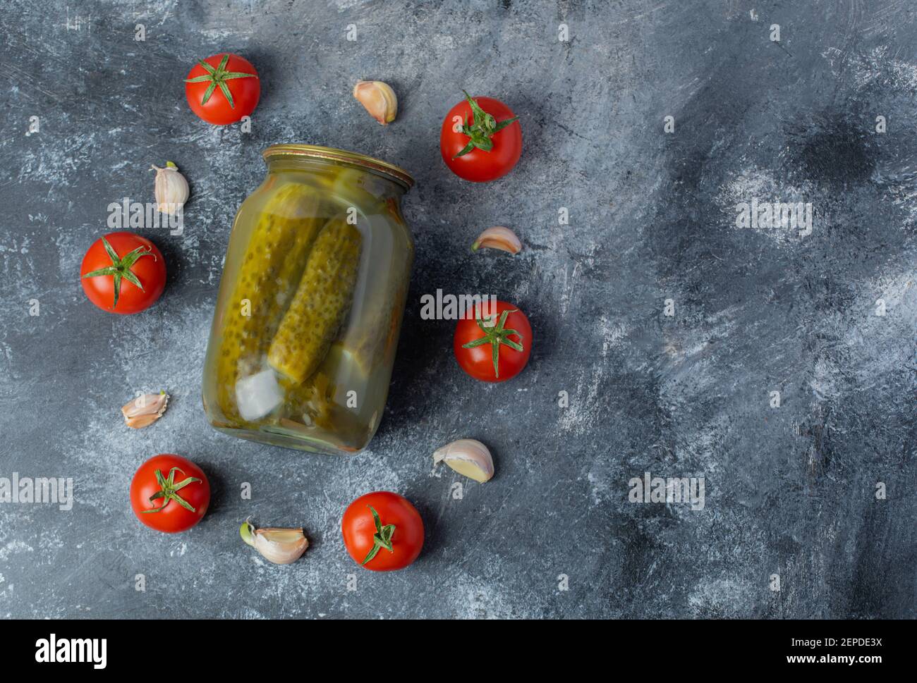 Top view of pickle jar with garlic and fresh tomatoes over grey ...