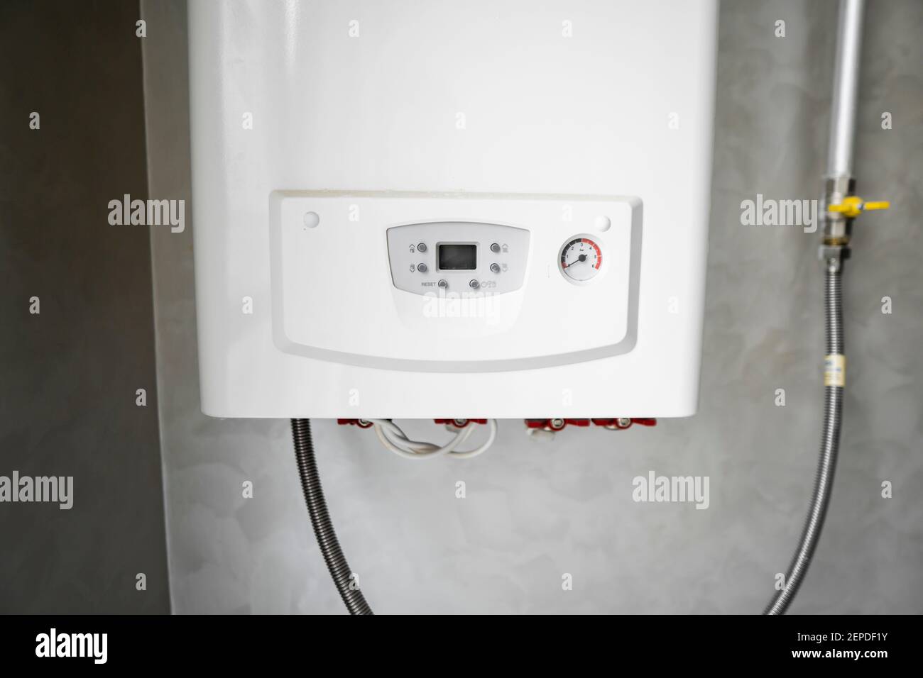 White modern home gas boiler mounted on a grey wall on a kitchen. Water ...