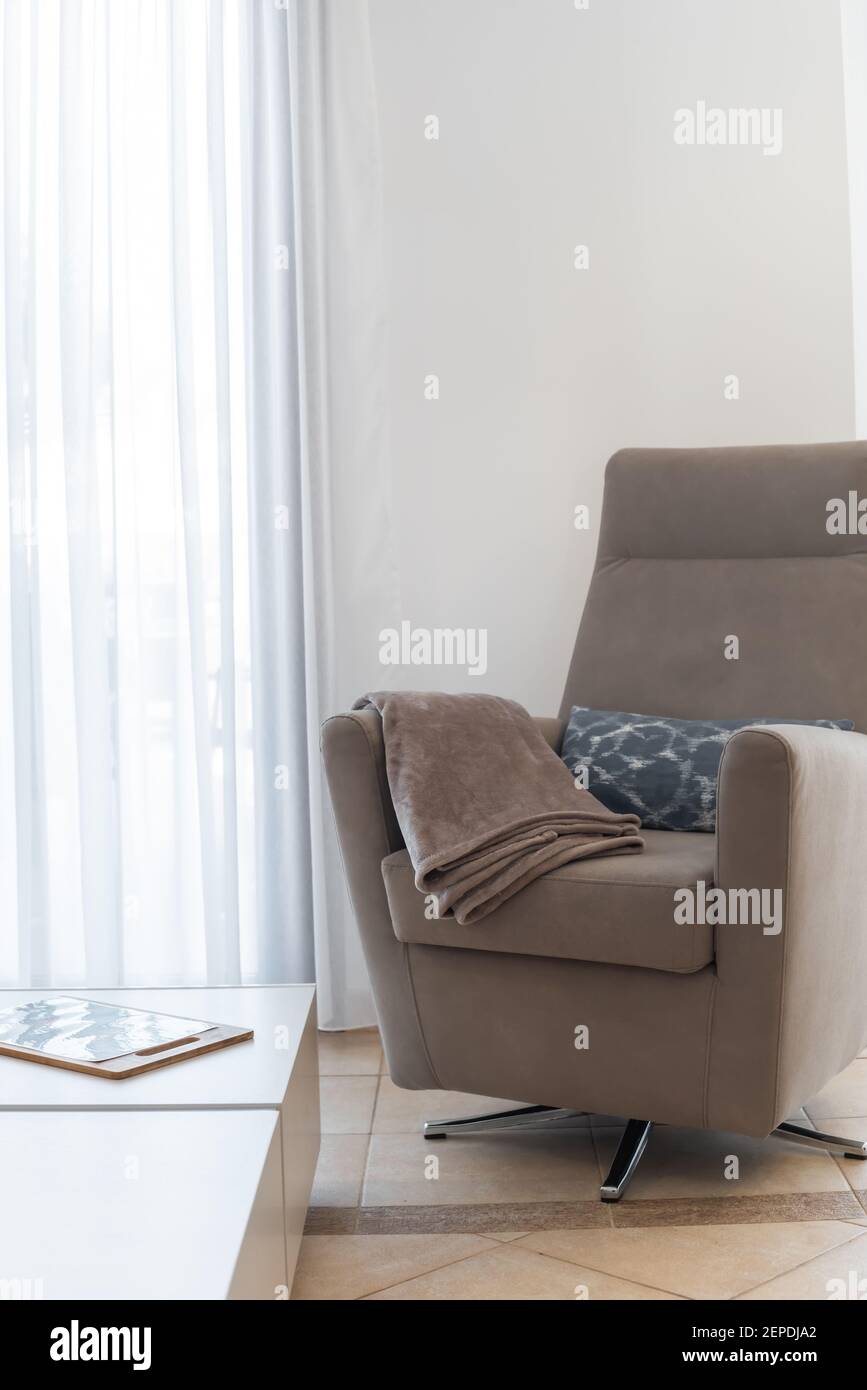 The beige sofa, chair beside a window with a curtain, letting in ...