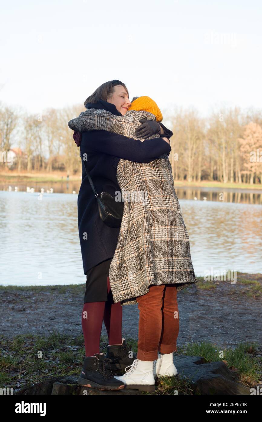 Two women hugging near the lake Stock Photo - Alamy