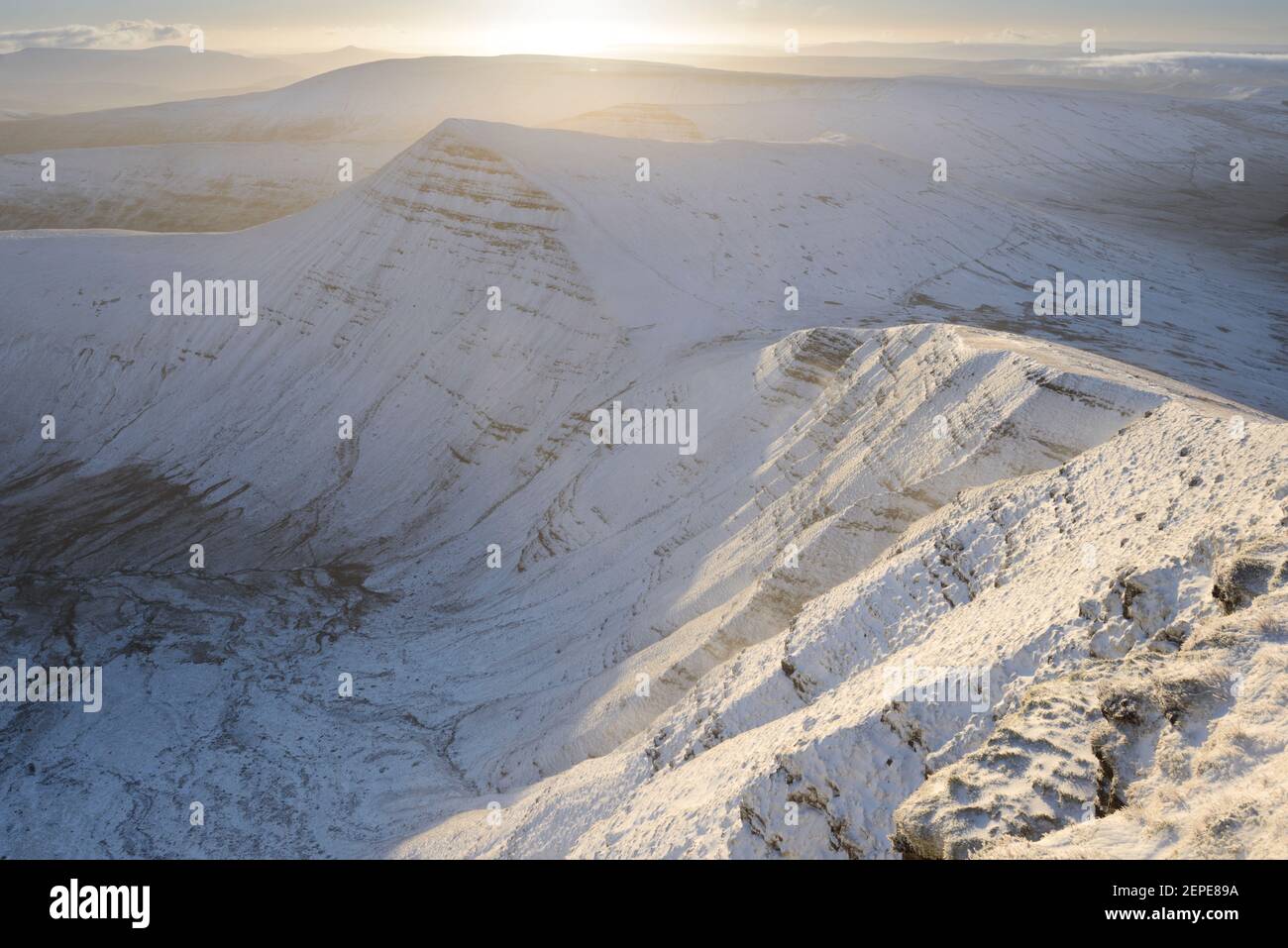 Snow covered Cribyn in the Brecon Beacons, illuminated by a break in ...