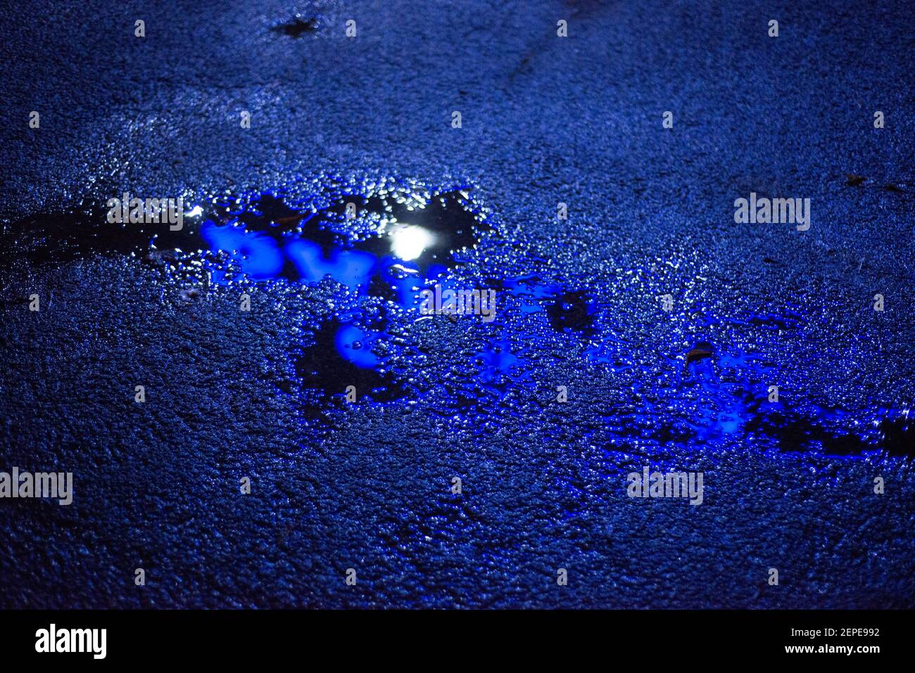 Puddle on the pavement with a blue light Stock Photo - Alamy
