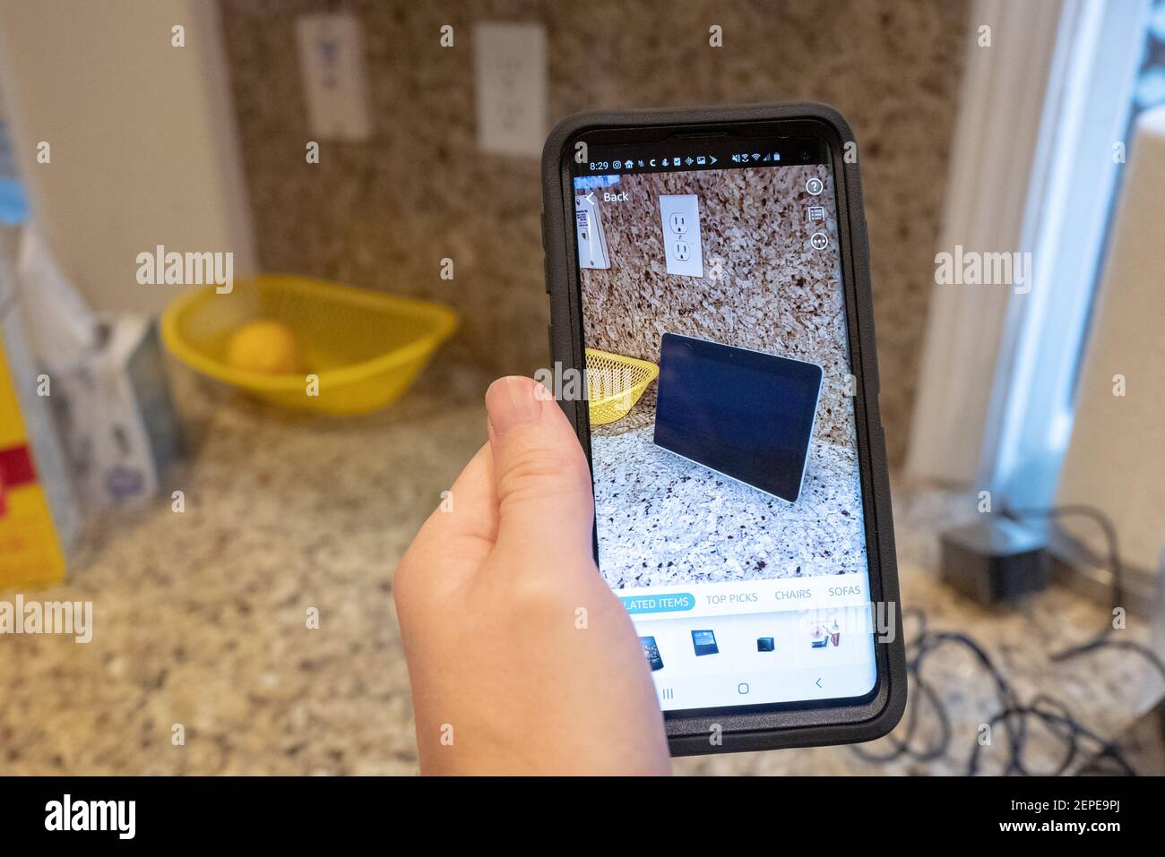 Hand of a man holding a smart phone and using Augmented Reality features in the Amazon shopping ...