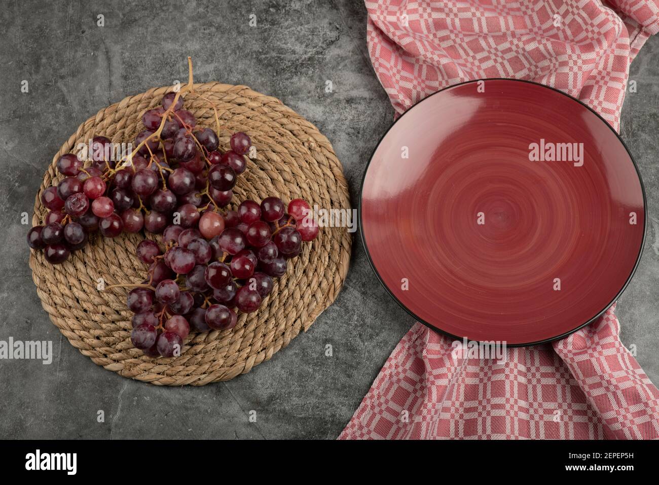 Cluster of red grapes and empty red plate on marble surface Stock Photo ...