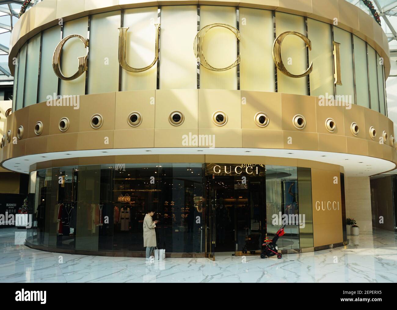 A shopper stands outside the boutique of Gucci at a shopping mall in ...