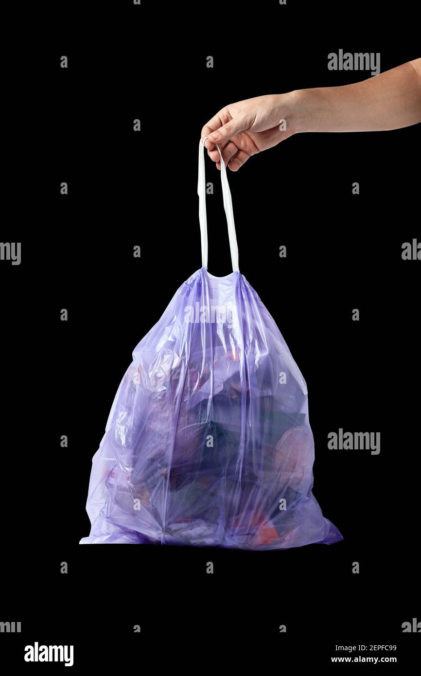 mens hand with full trash bag isolated on black background. garbage ...