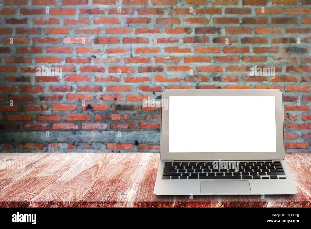 Blank screen laptop on wooden shelves with blurred brick wall ...