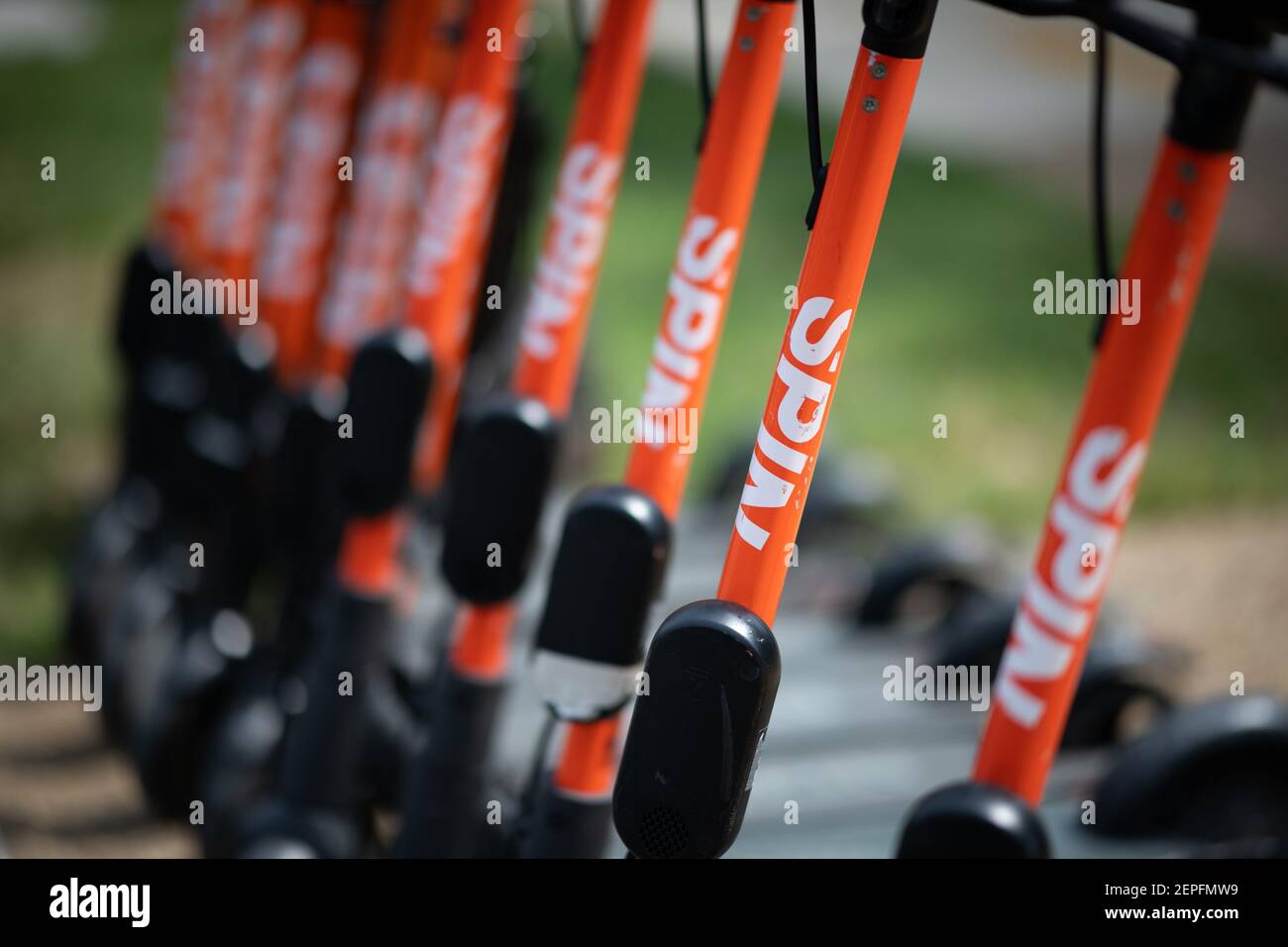 A line of Spin dockless scooters parked on the sidewalk as seen in ...