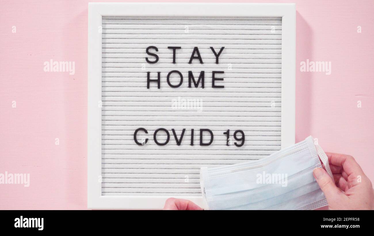 Flat lay. STAY HOME and COVID-19 sign on message board with a blue ...