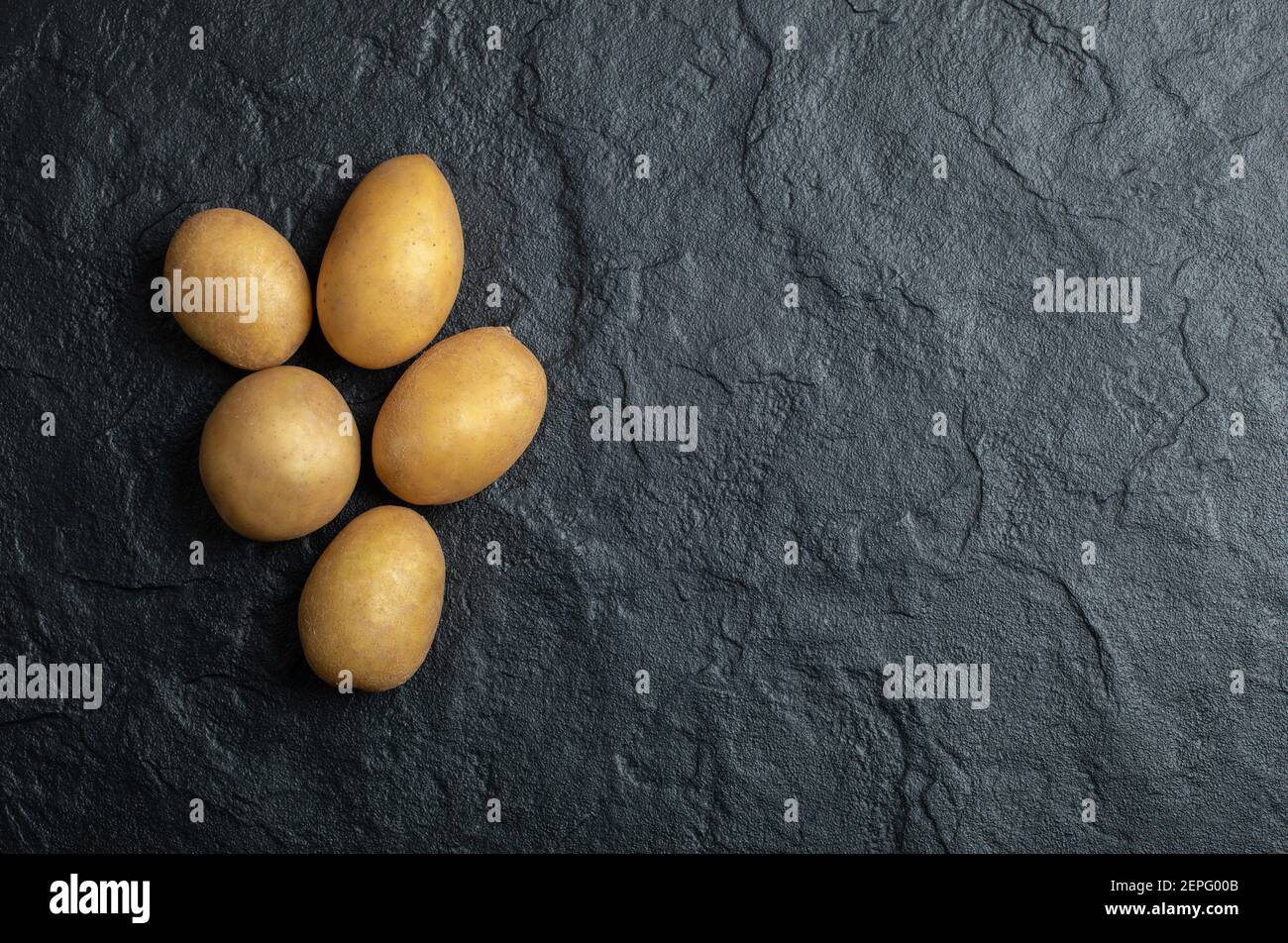 Top view of pile of potatoes. Fresh potatoes on black stone background ...