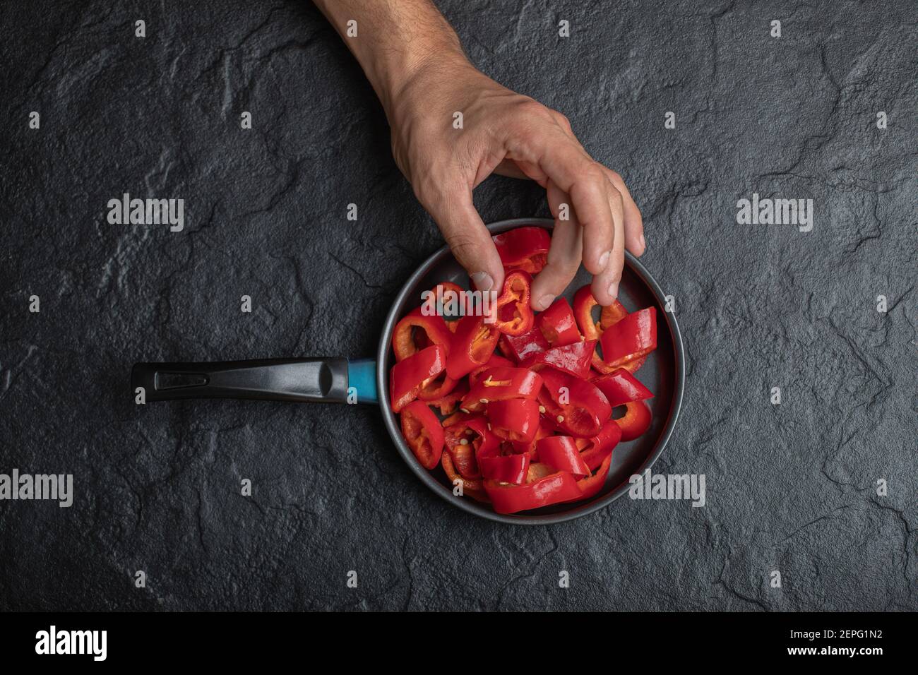 Male hand taking sliced red bell peppers from black background Stock ...