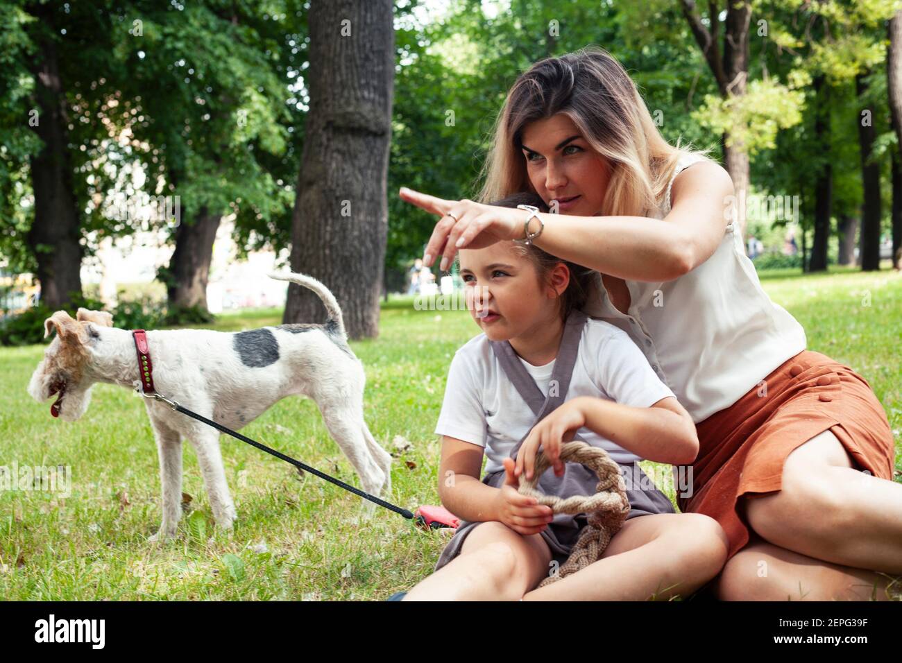 young pretty caucasian mother walking with little cute daughter and dog ...
