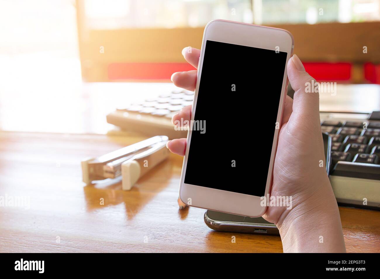 Hand holding mobile smart phone with office desk vintage wood working ...
