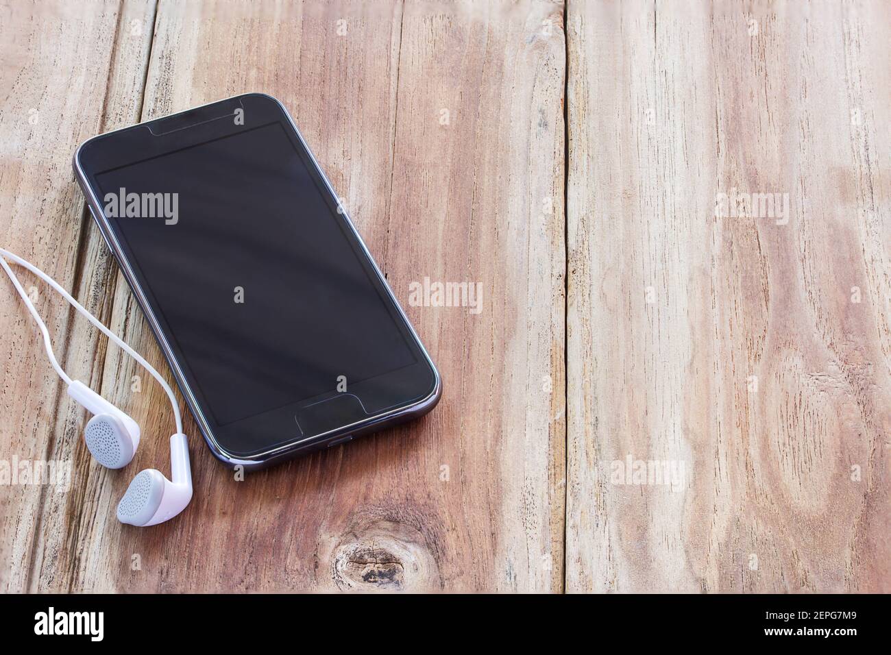 Smart phone and headphones lay on an old wooden table with copy space ...
