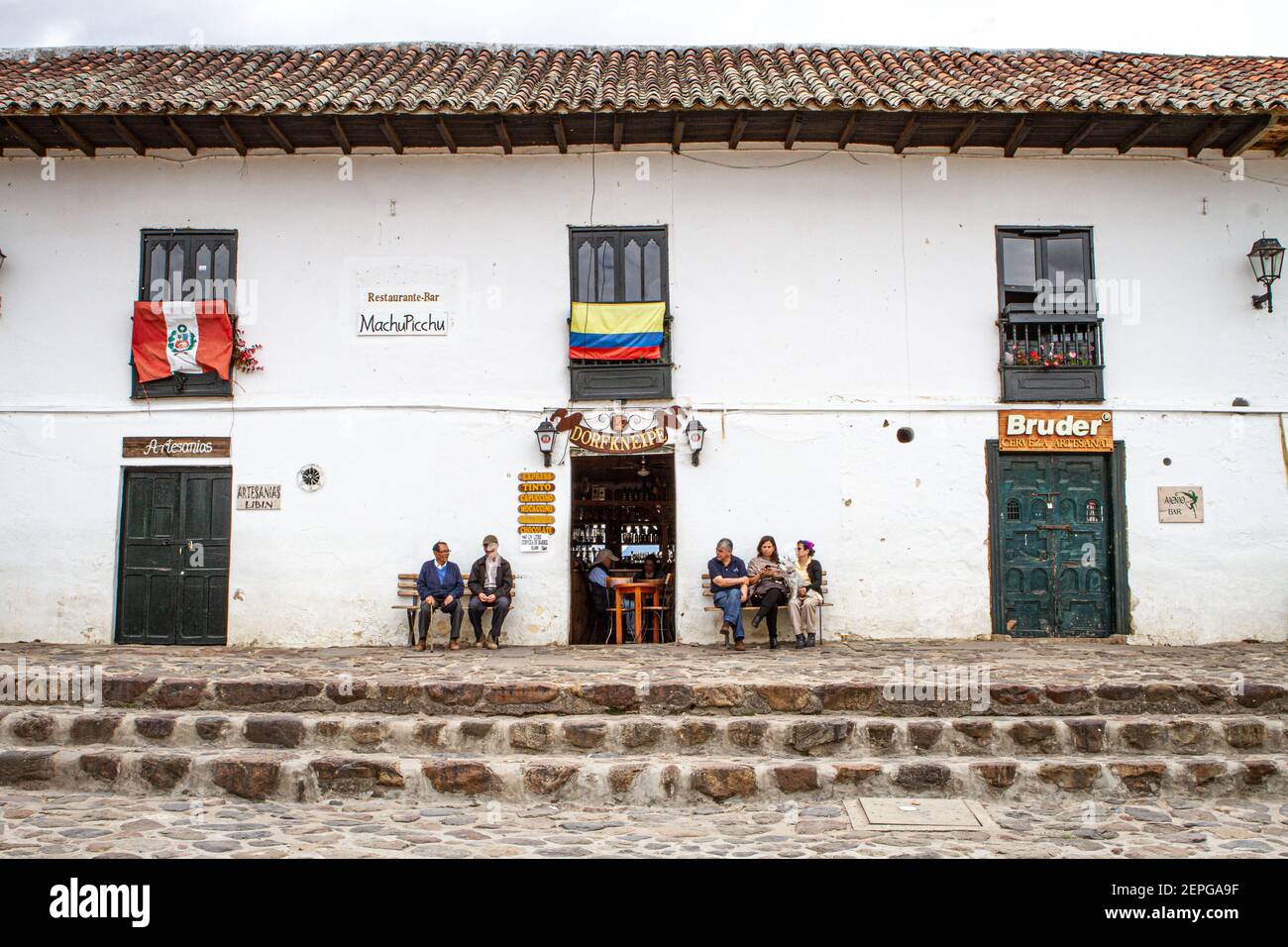 5 people. sitting outside bar and store.Villa de Leyva main square 500 year old town. Mountain ...