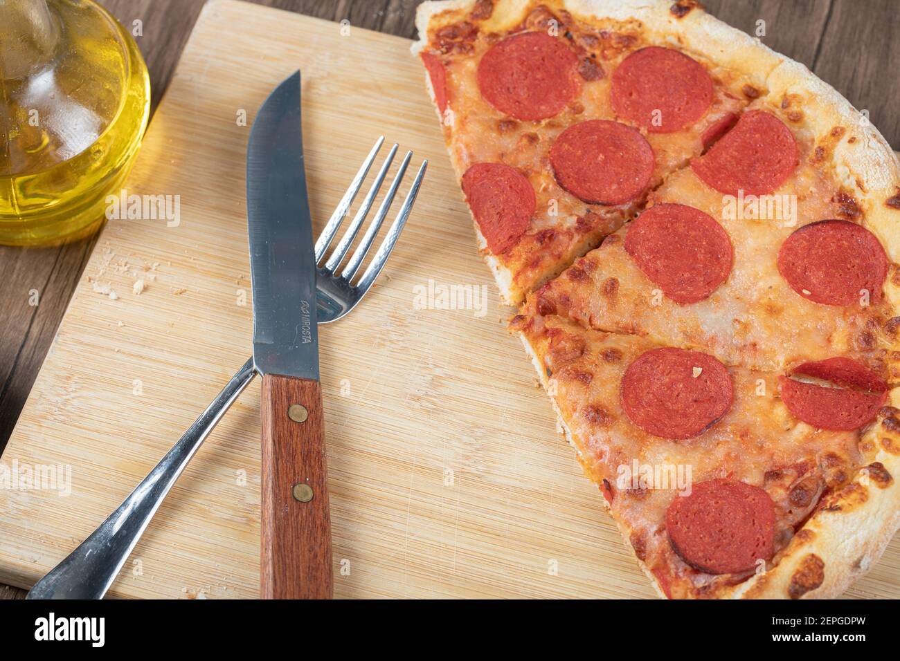 Close up photo of Half of pepperoni pizza on wooden plate with sauces and oil Stock Photo - Alamy