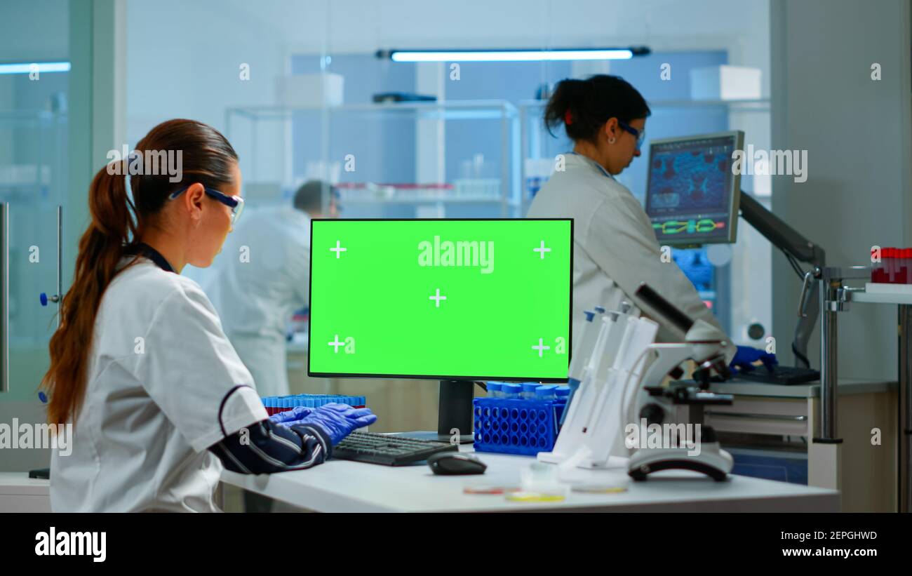 Medical research scientist working on pc with green screen mock up ...