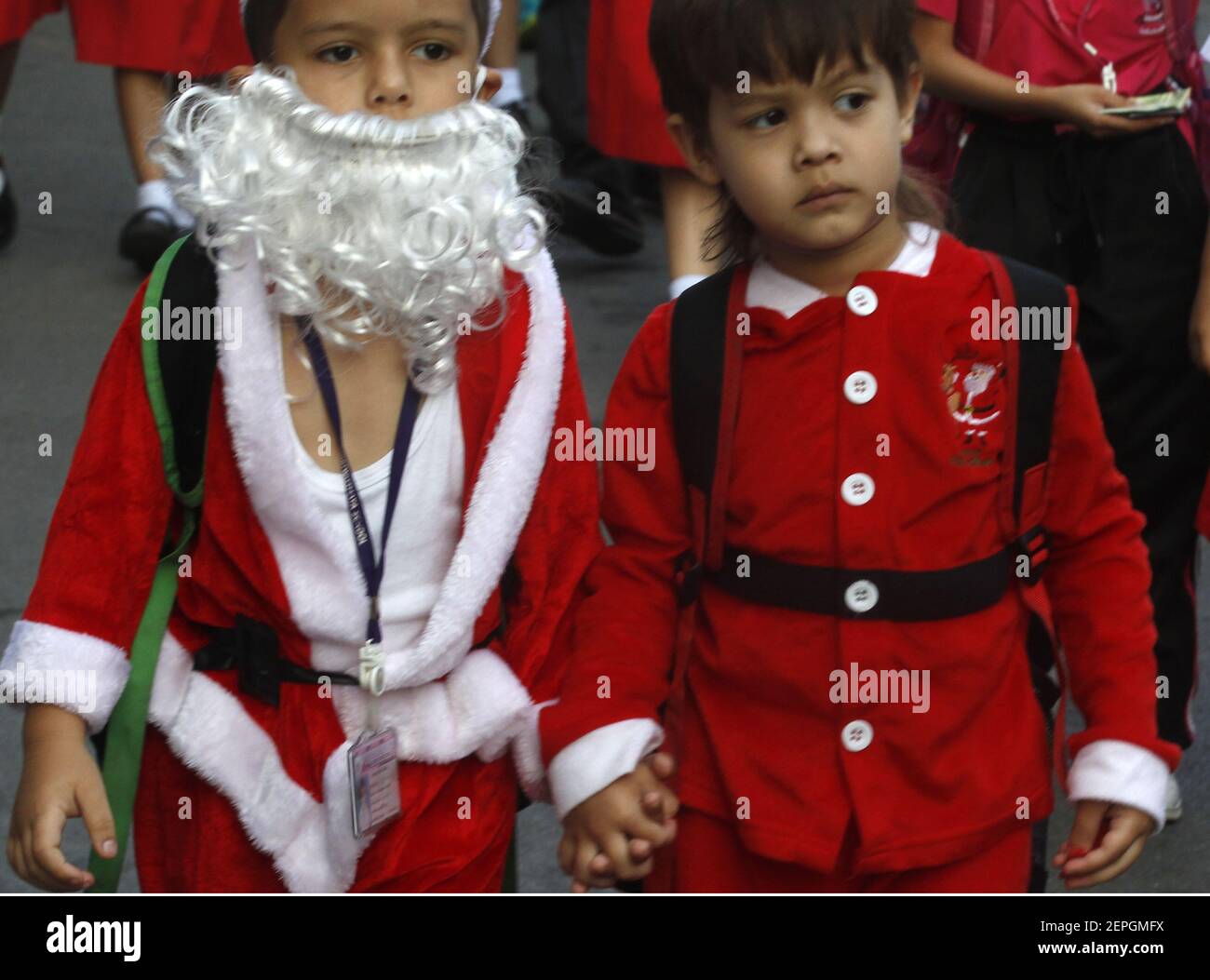 kids dressed in Santa Claus costumes hold hands during the Christmas ...