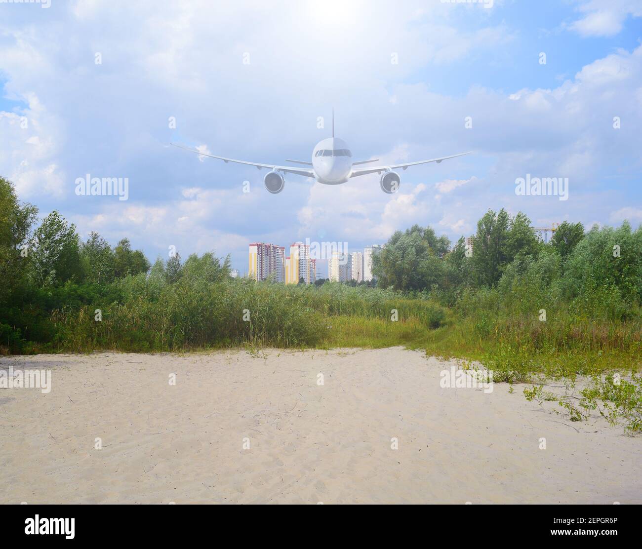 Passenger plane over a house in the city near nature. The sun is ...