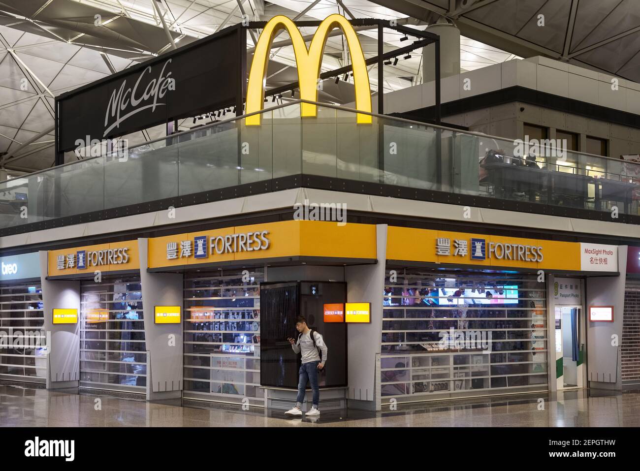 A man stands under a large McDonald's fast-food restaurant logo and ...