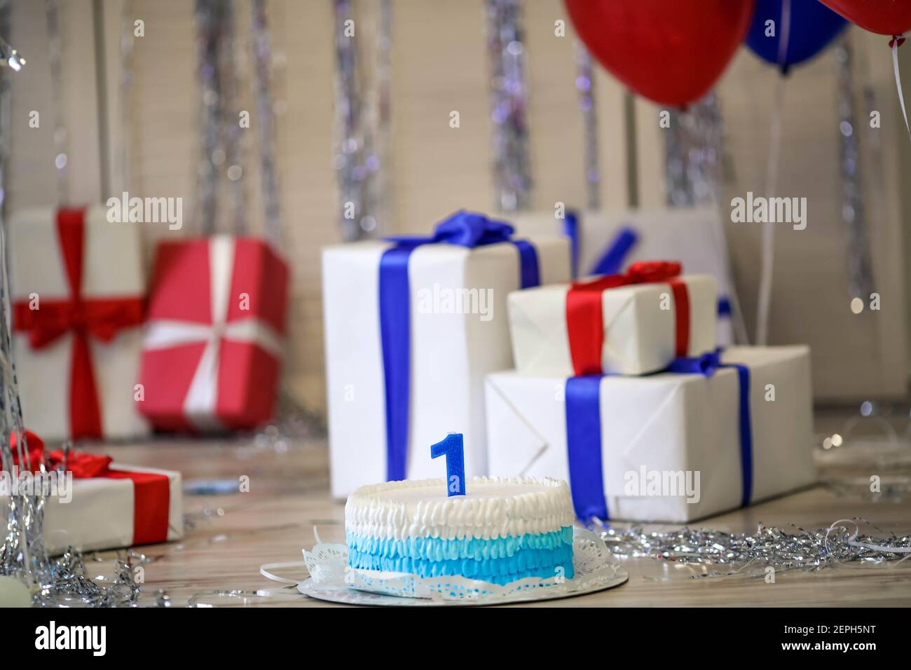 Birthday cake with a candle 1 year and boxes with gifts Stock Photo - Alamy