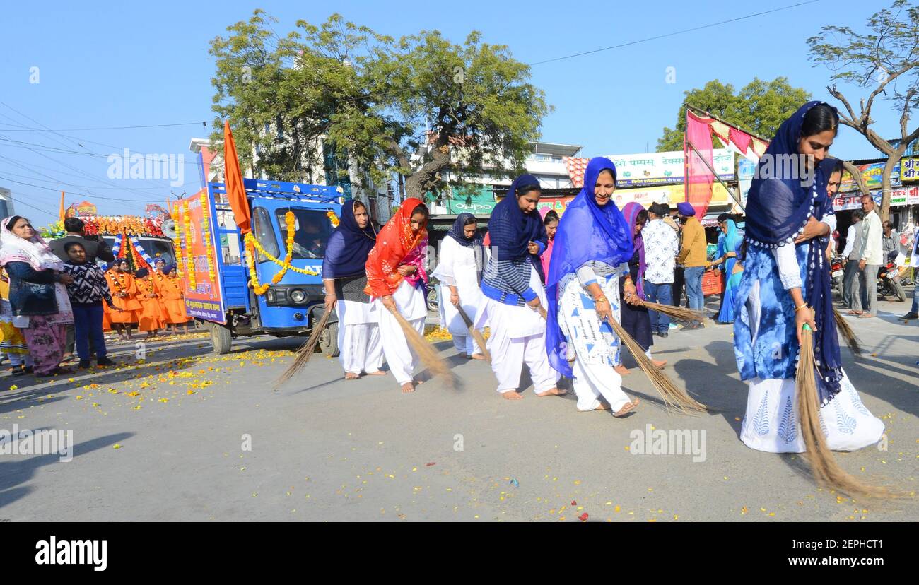 Sikh devotees clean the road for 'Guru Granth Sahib' during a ...