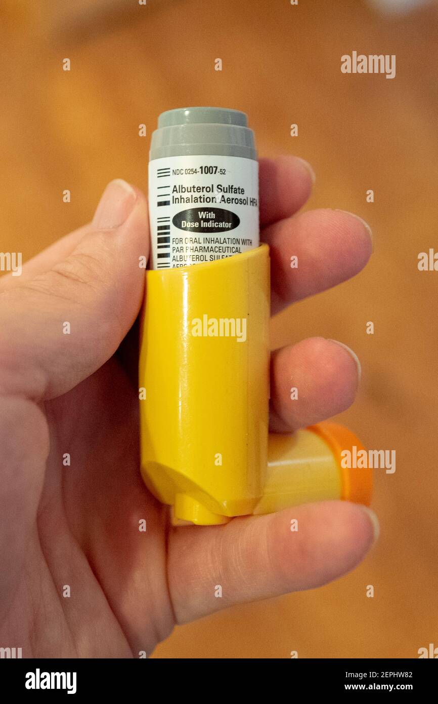 Close-up of human hand of a man holding an albuterol sulfate inhaler ...