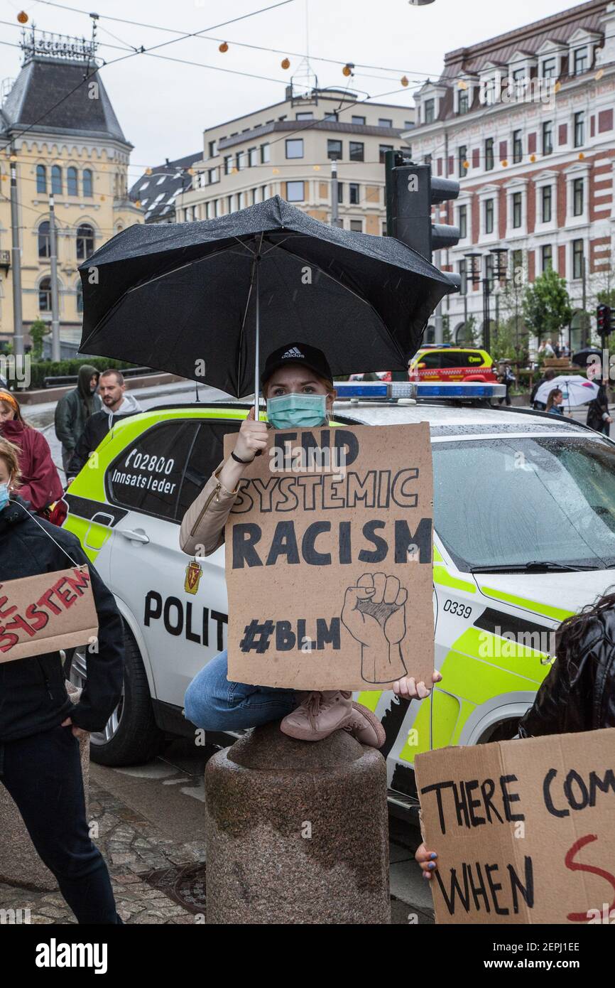 A protester holding a BLM placard and an umbrella during the ...
