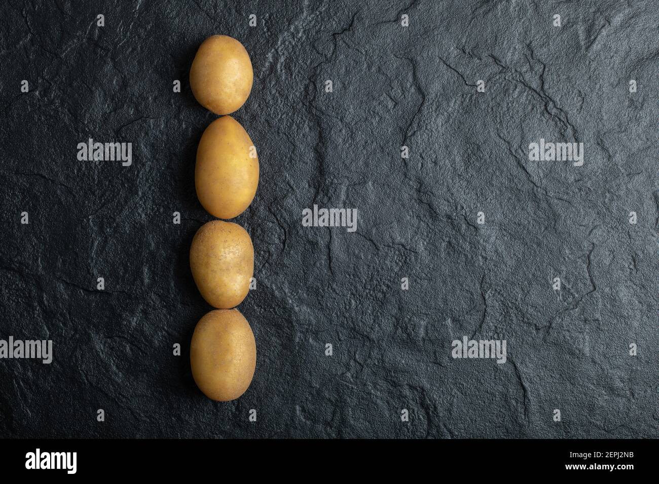 Top view of fresh potatoes in a row on black stone background Stock ...