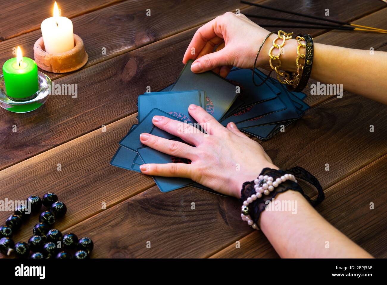 Fortune-teller's hands with cards of predictions on a wooden background ...