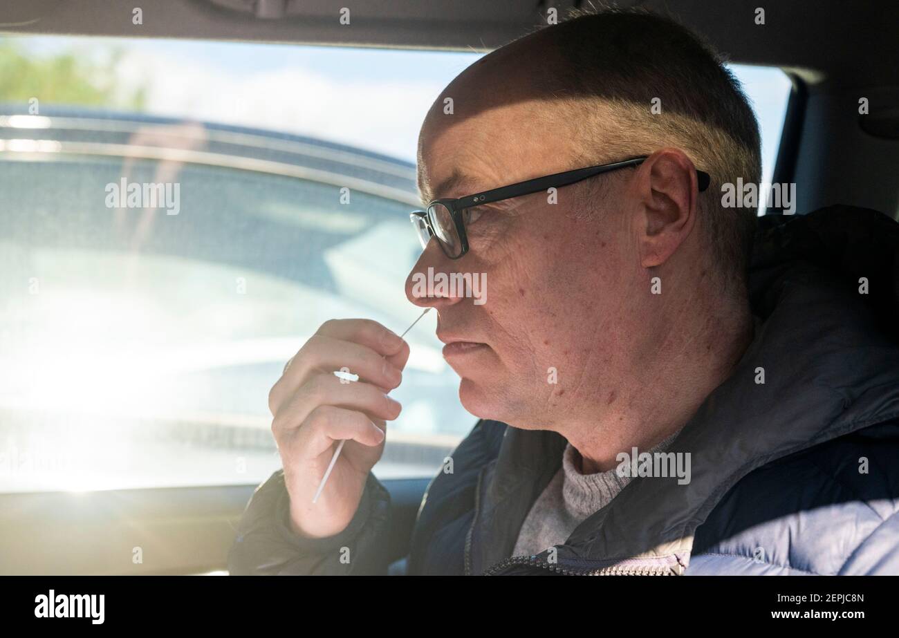 Male person using a coronavirus COVID-19 fast lateral flow self testing ...