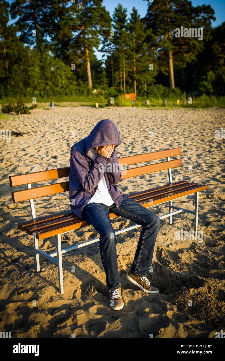Sad Young Man sit on the Bench outdoor Stock Photo - Alamy