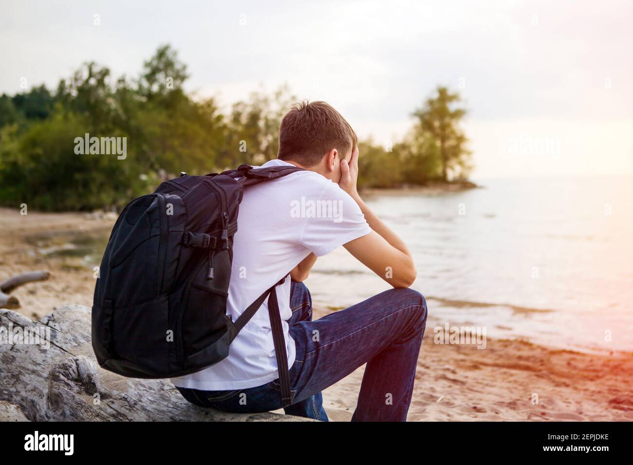 Sad Man with Backpack sit on the Log at the Seaside Stock Photo - Alamy